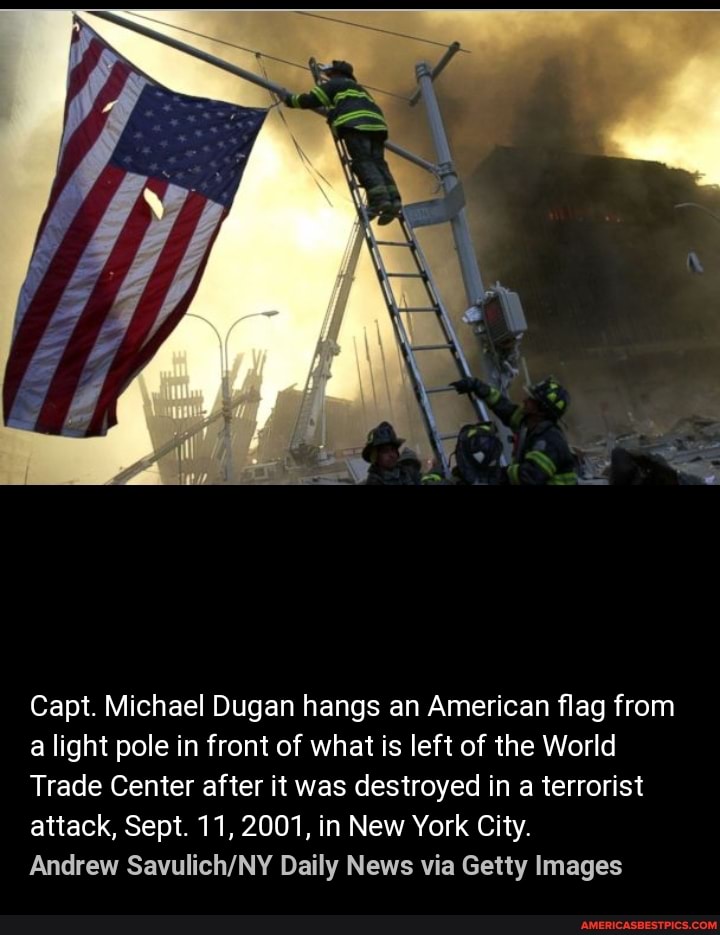 Capt. Michael Dugan hangs an American flag from a light pole in front ...
